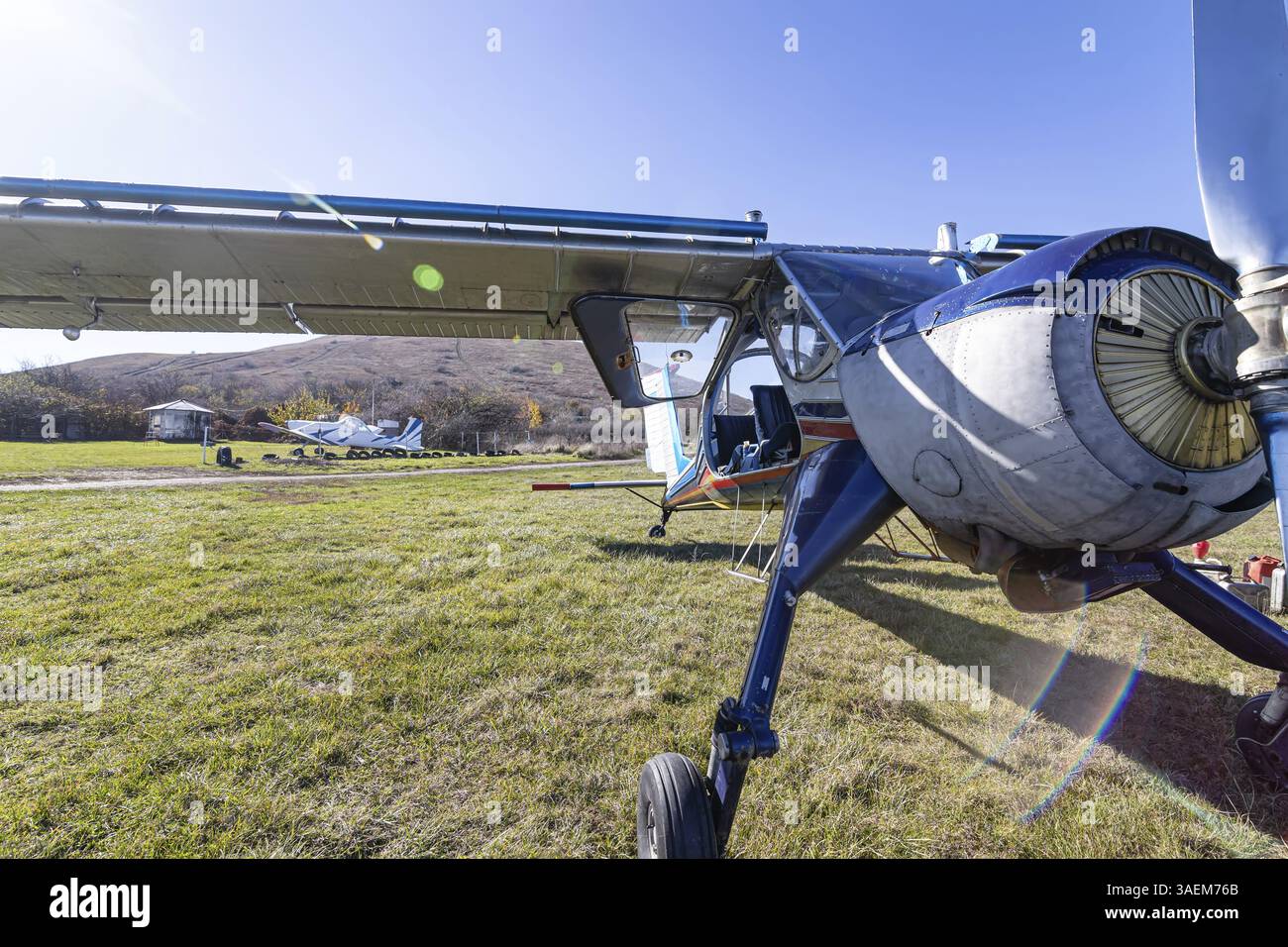 A small light-engine aircraft stands on a field airfield preparing for ...