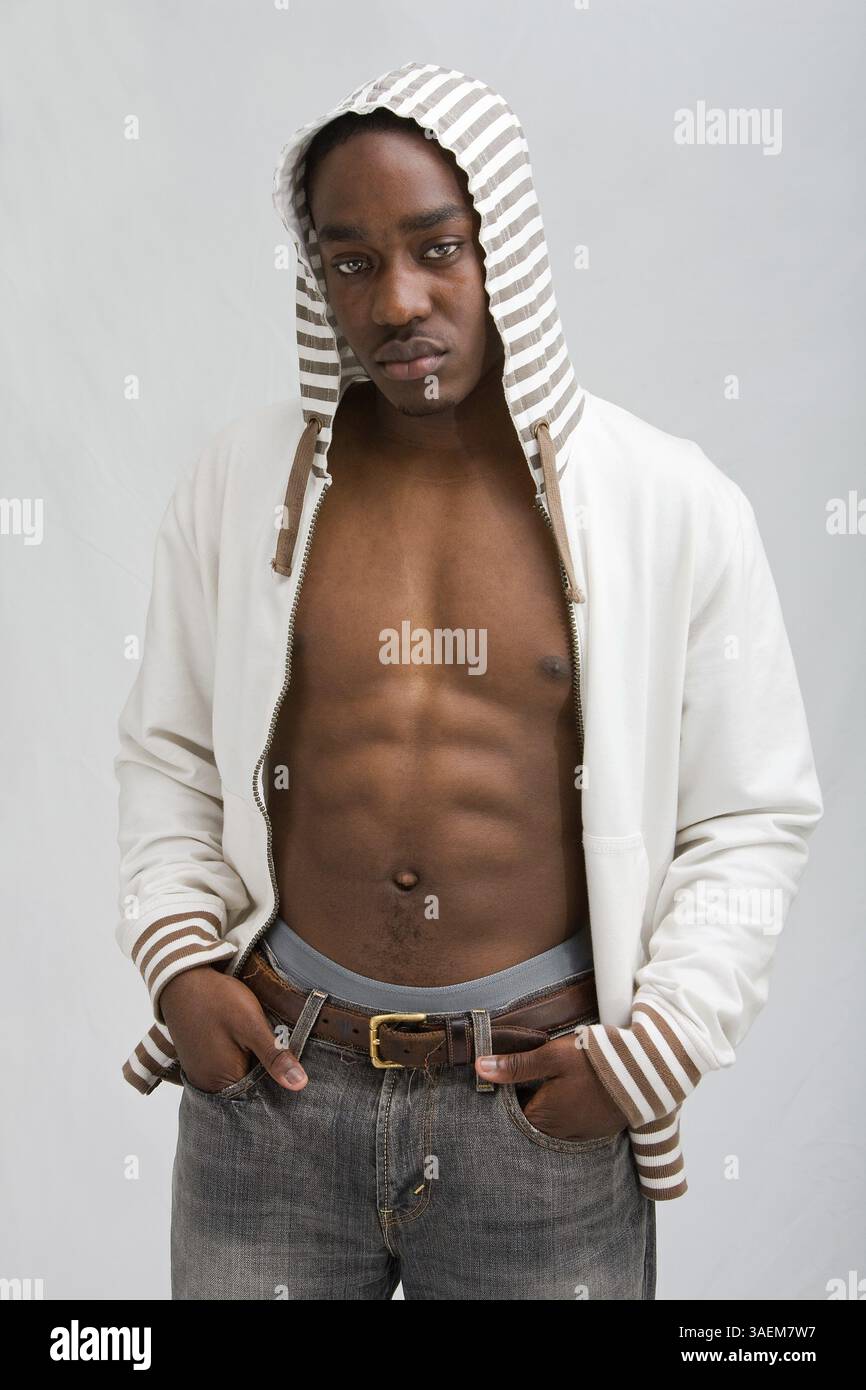 Young dark skinned handsome guy standing like a macho with both hands ...