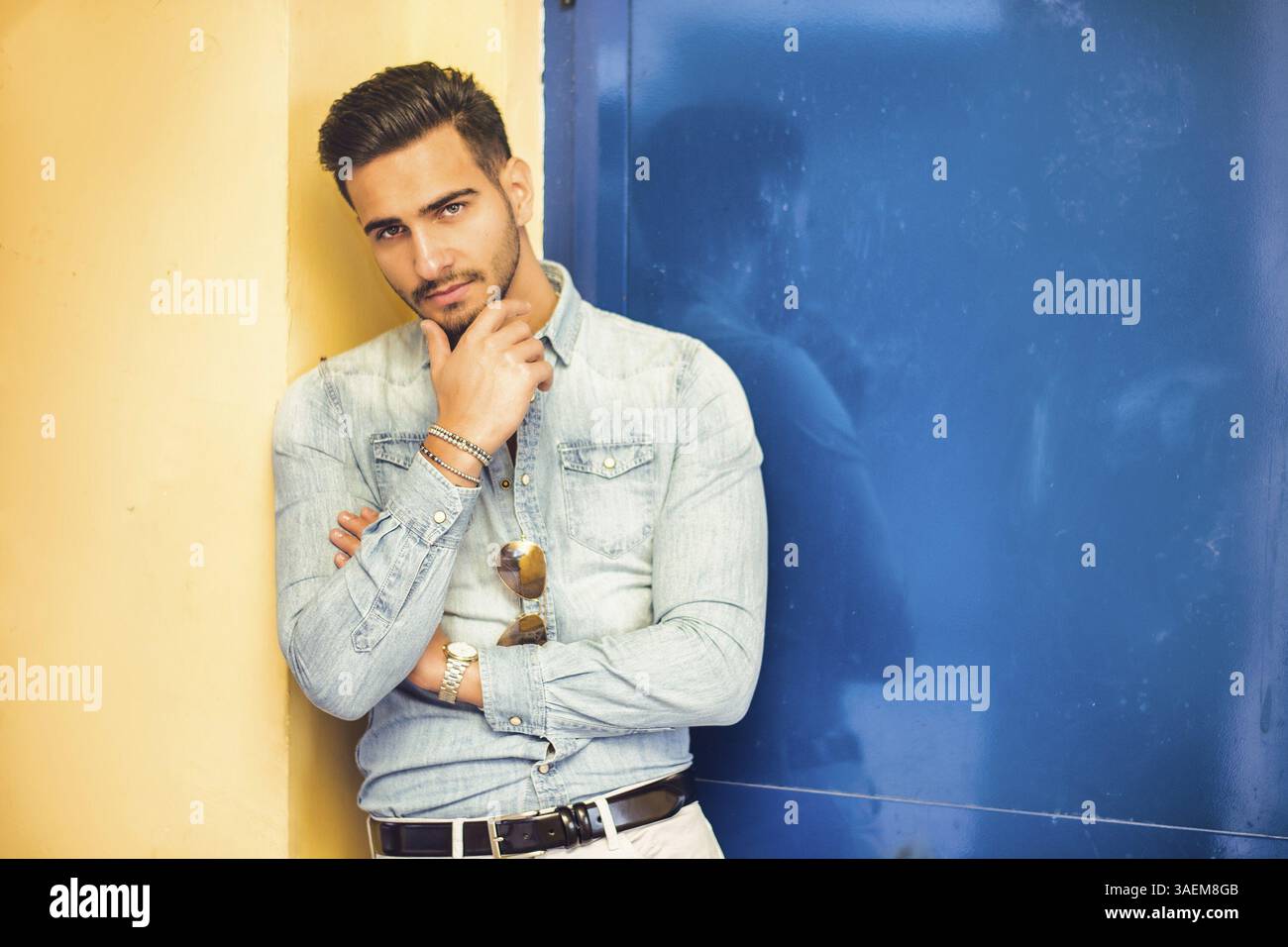 A man leaning against a wall with his hand on his chin Stock Photo - Alamy