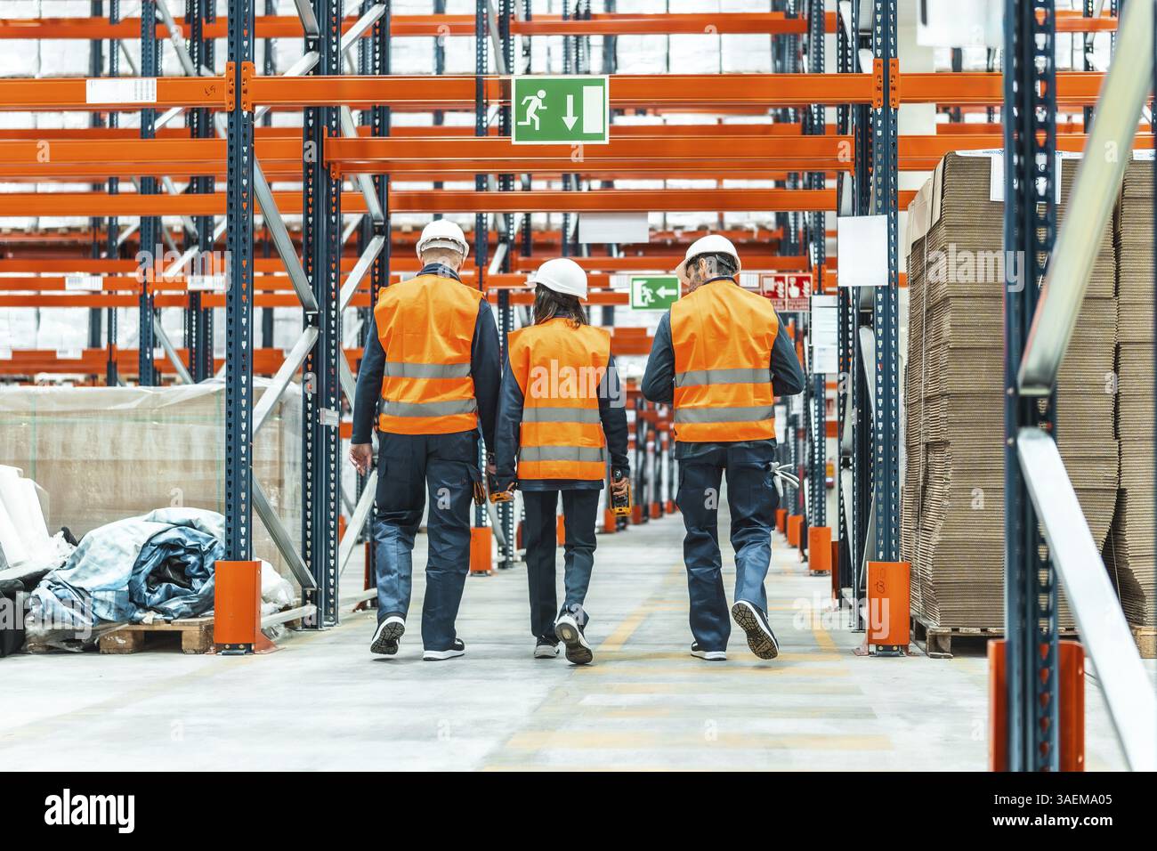 Warehouse workers wearing high visibility vests and hard hats are ...