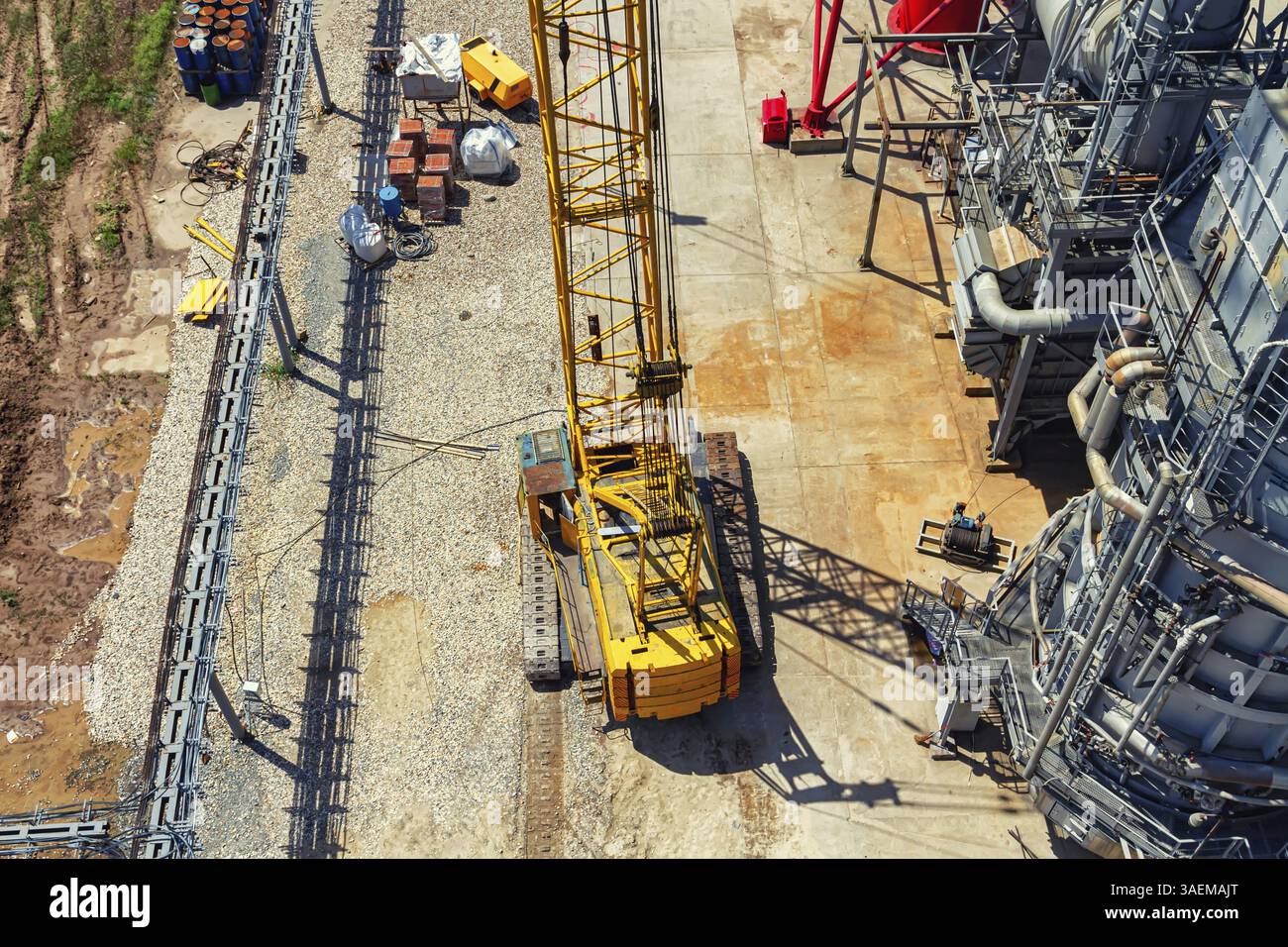 A large yellow crawler crane stands at the bottom of the reactor base ...