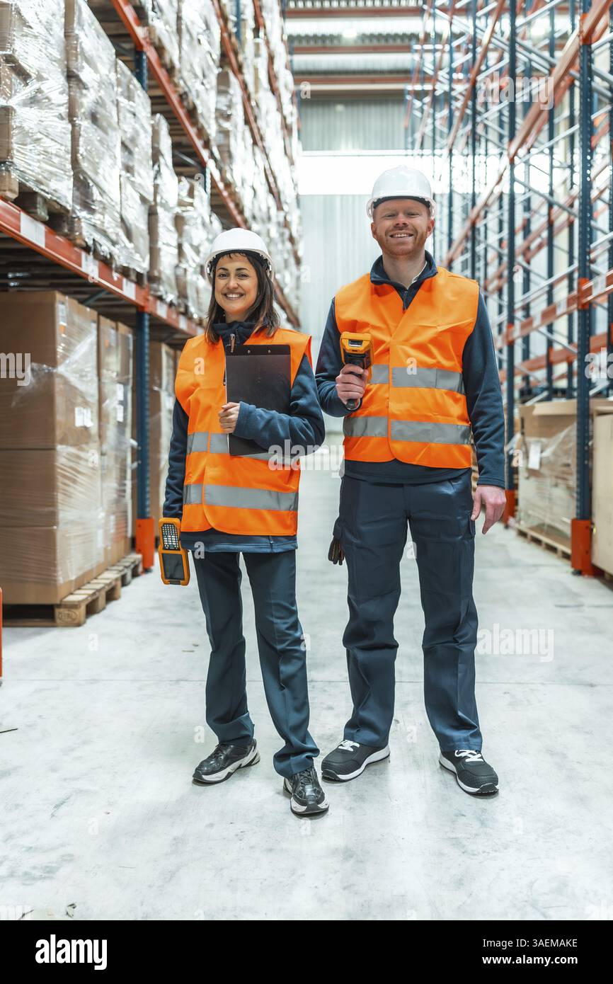 Two warehouse workers are managing inventory, holding barcode scanner ...