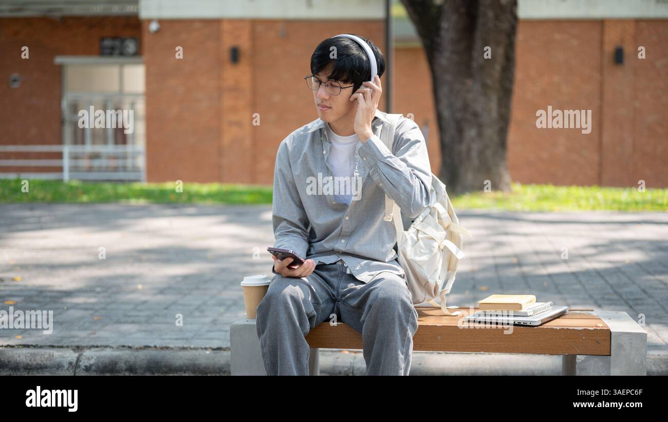 An asian man with glasses is closing eyes listening to music in his ...