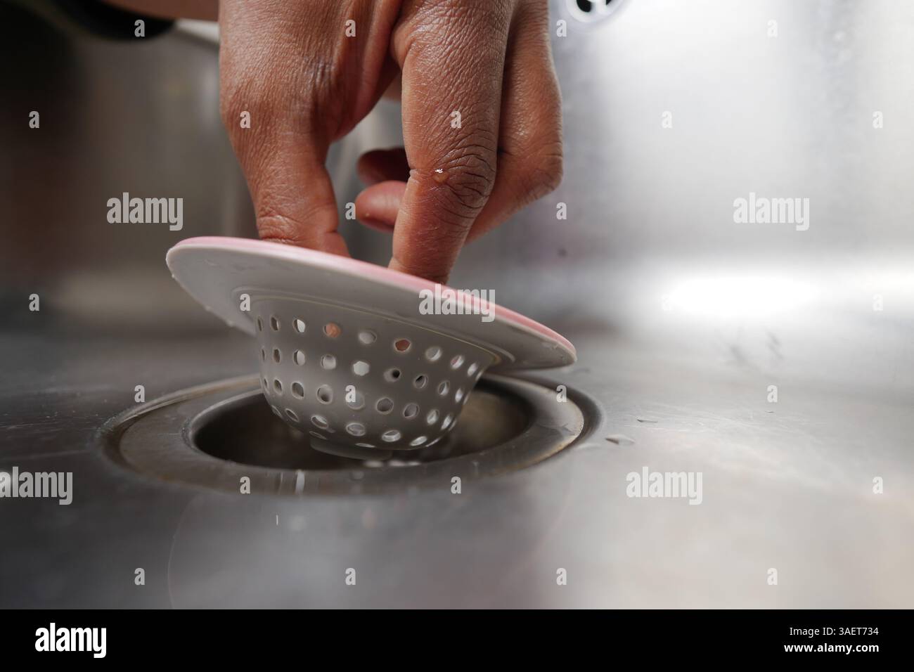 Kitchen hand placing a sink strainer into a drain for cleanup Stock ...