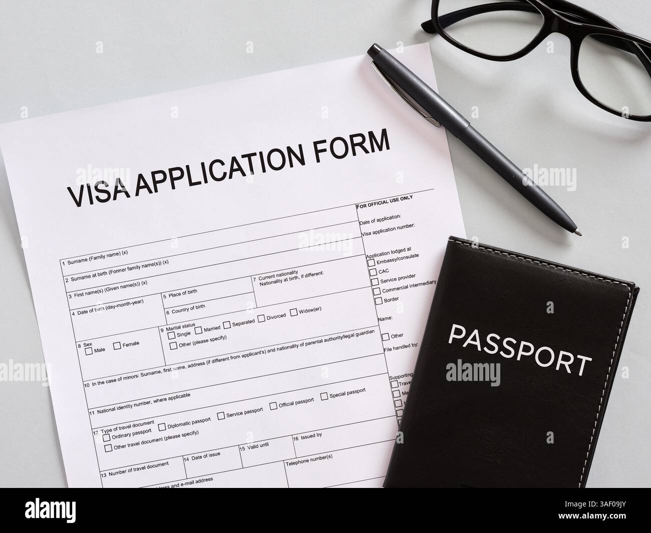 Visa application form with passport, pen and eyeglasses laying on gray table, preparing for ...