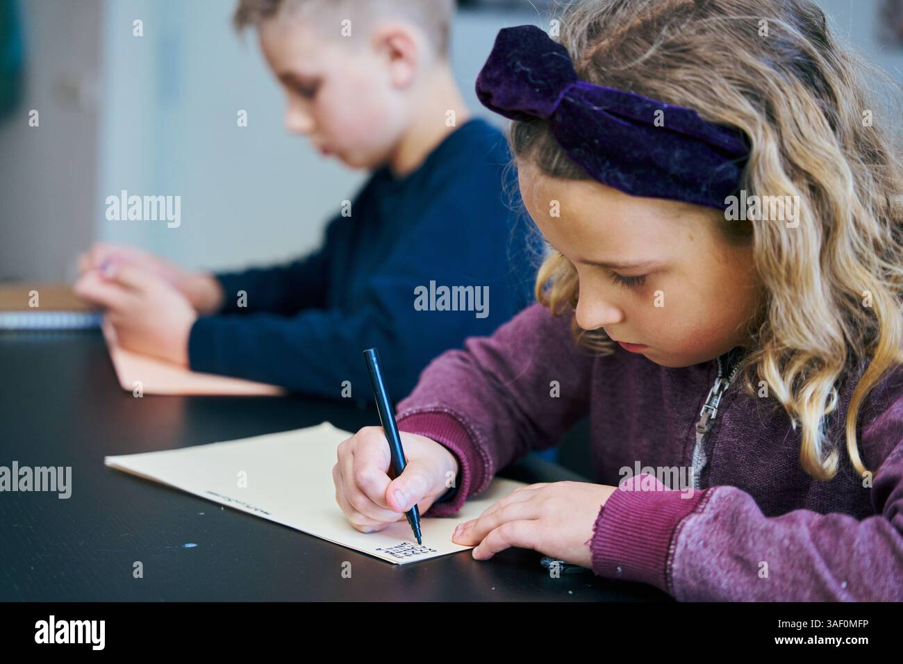 Pupils writing on notebook at school desk Stock Photo - Alamy
