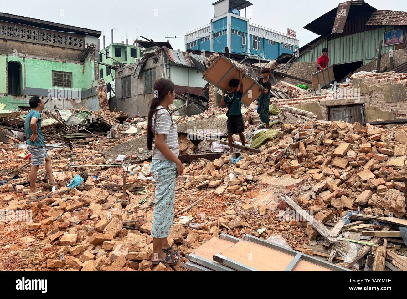People clean debris from damaged buildings in the aftermath of an ...