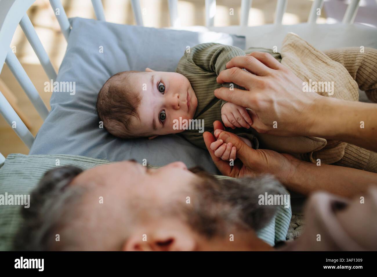 Father putting the baby to sleep, lying next to him in the crib Stock ...
