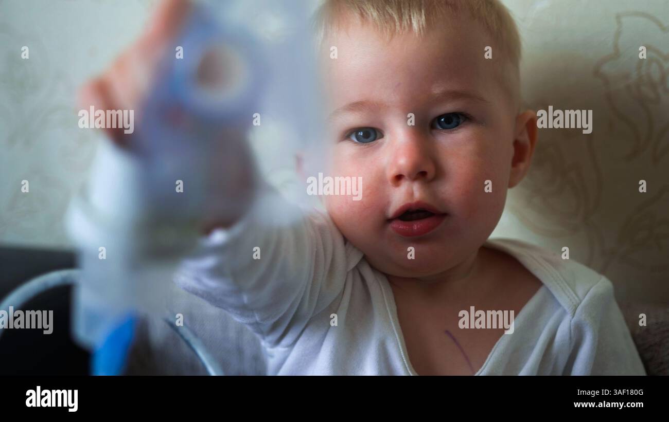 Baby holding oxygen mask during inhalation therapy Stock Photo - Alamy