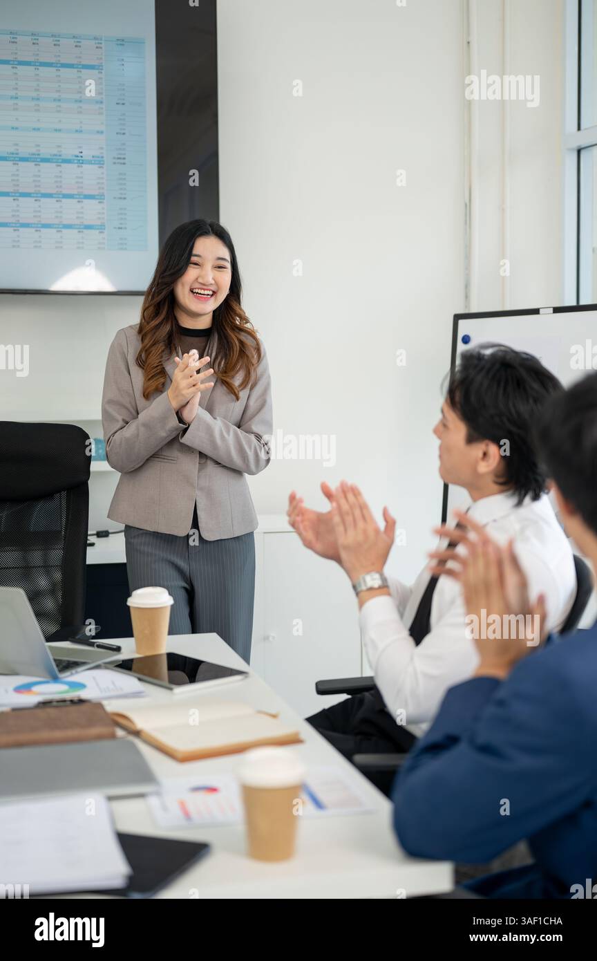 Smiling female office worker is standing and clapping her hands ...