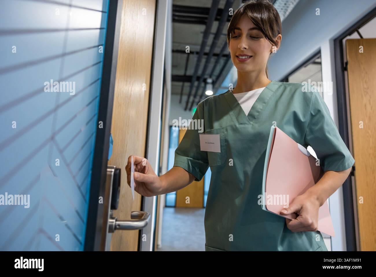 Adult female doctor placing key card on digital access reader in ...