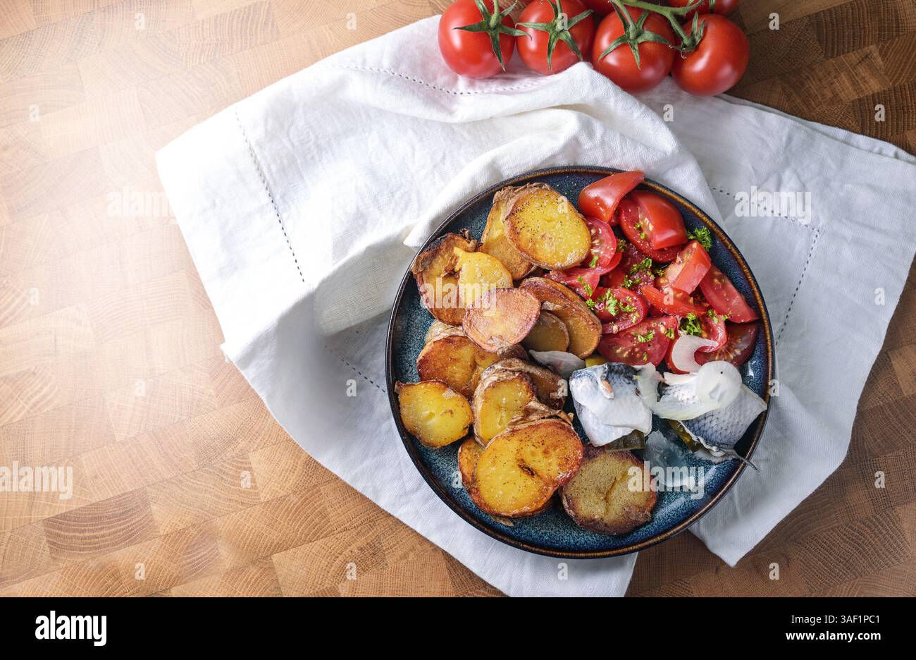 Fried potatoes, tomatoes and rollmops, traditional fish meal with ...