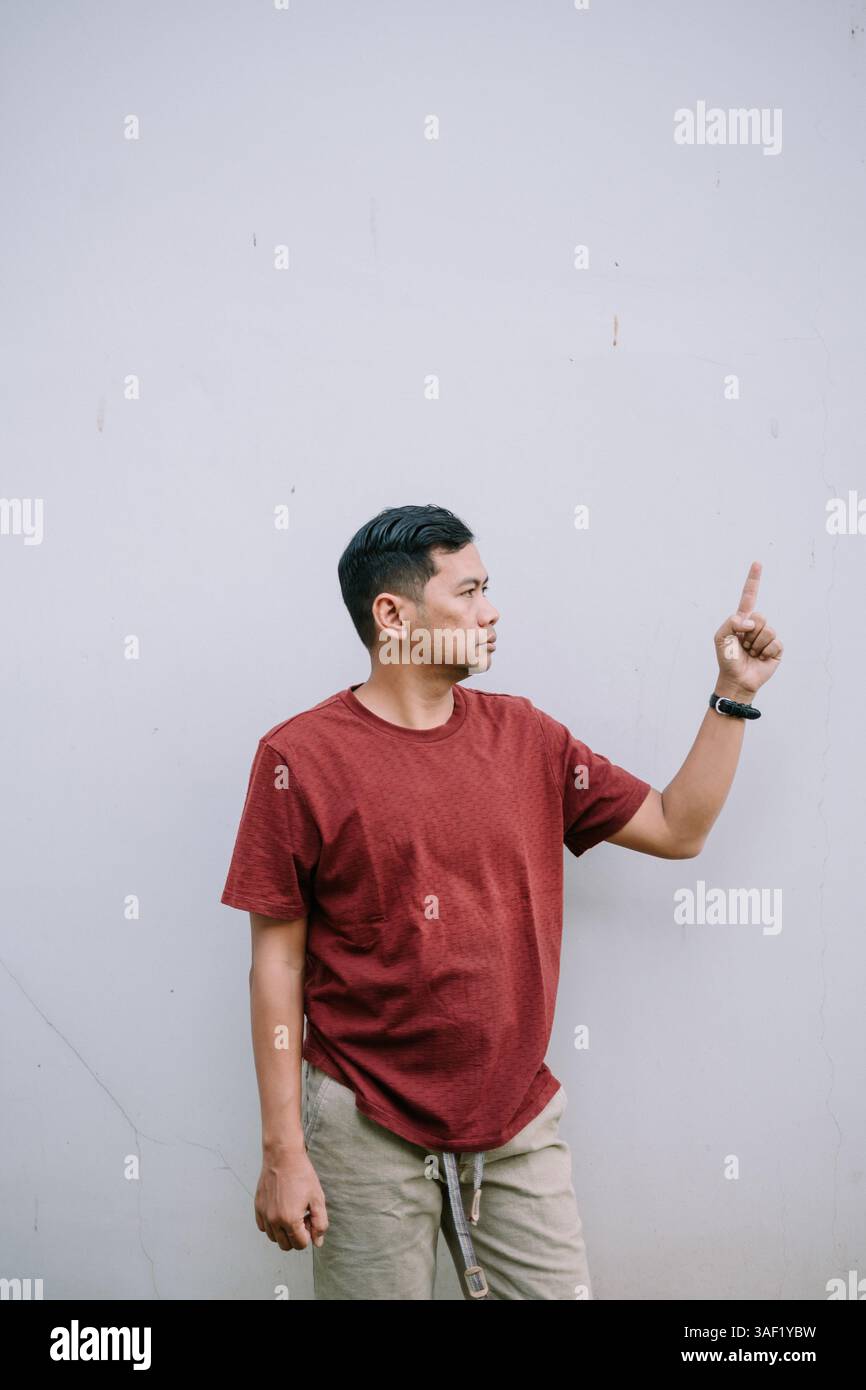 A man points upward near a white wall, a symbol of direction and ...
