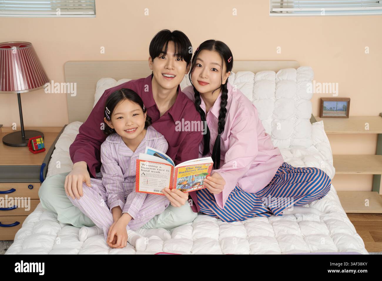 A family sitting in bed and reading a storybook Stock Photo - Alamy