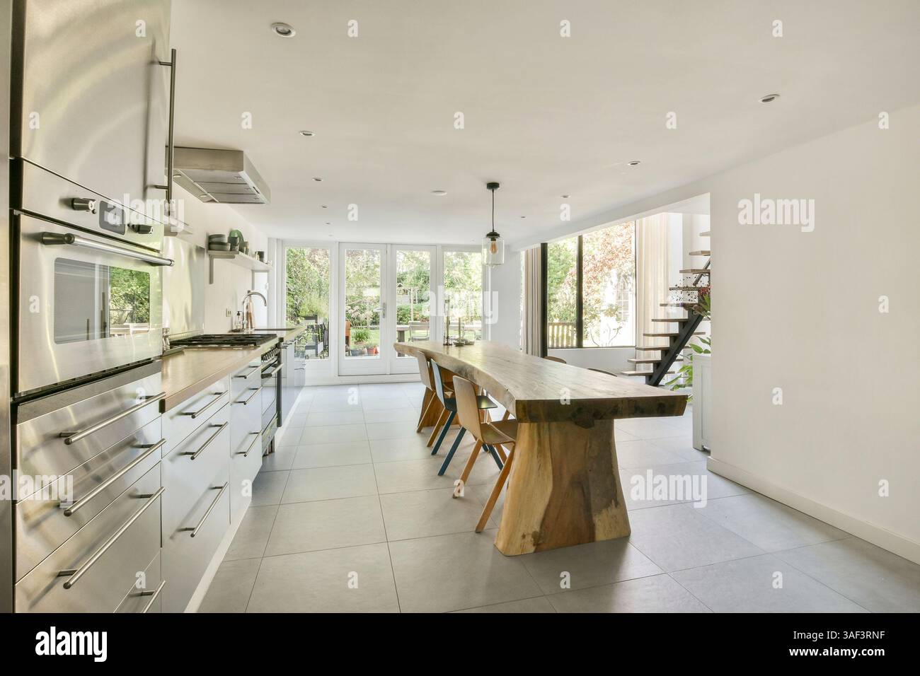 A spacious modern kitchen featuring sleek metallic cabinets, a wooden ...