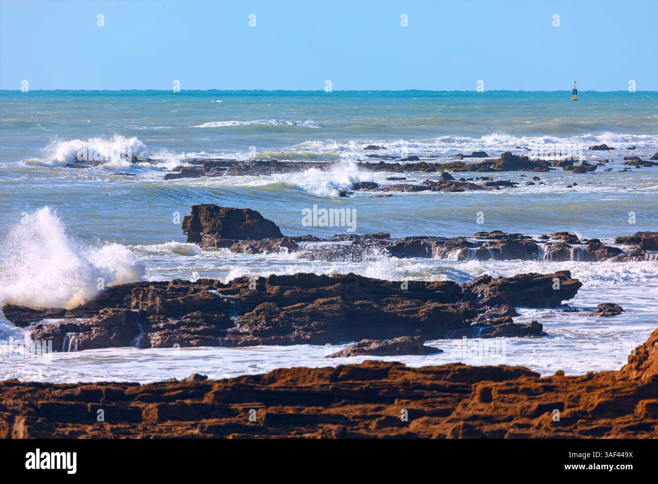 Powerful waves crash against jagged rocks, creating a dramatic coastal ...