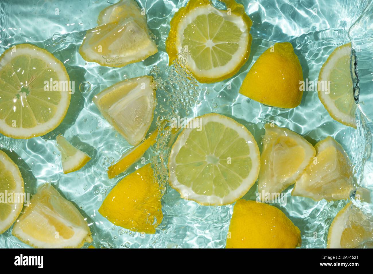 Refreshing turquoise citrus background with floating yellow lemon pieces Stock Photo - Alamy