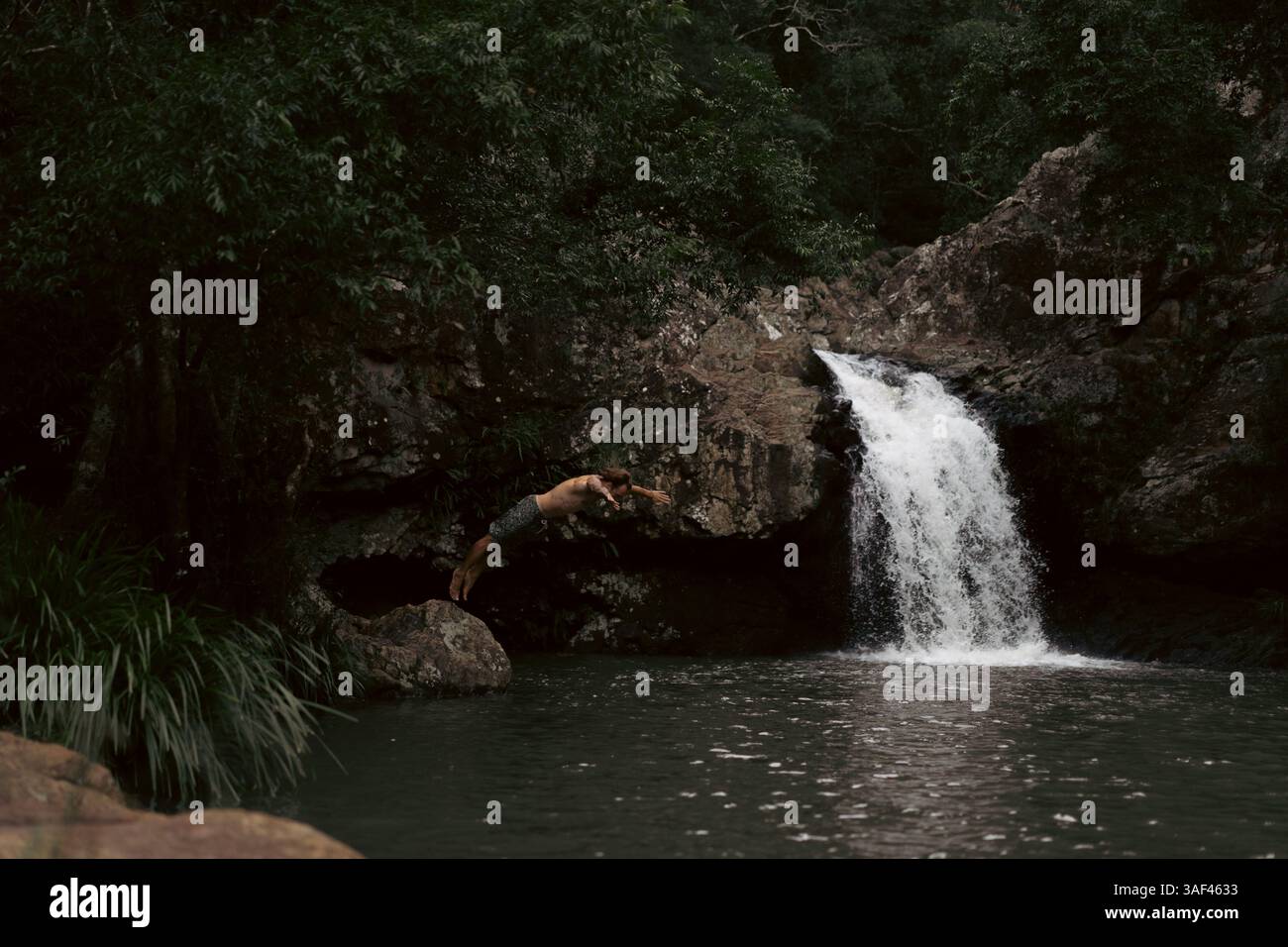 Man jumping into a waterfall Stock Photo - Alamy