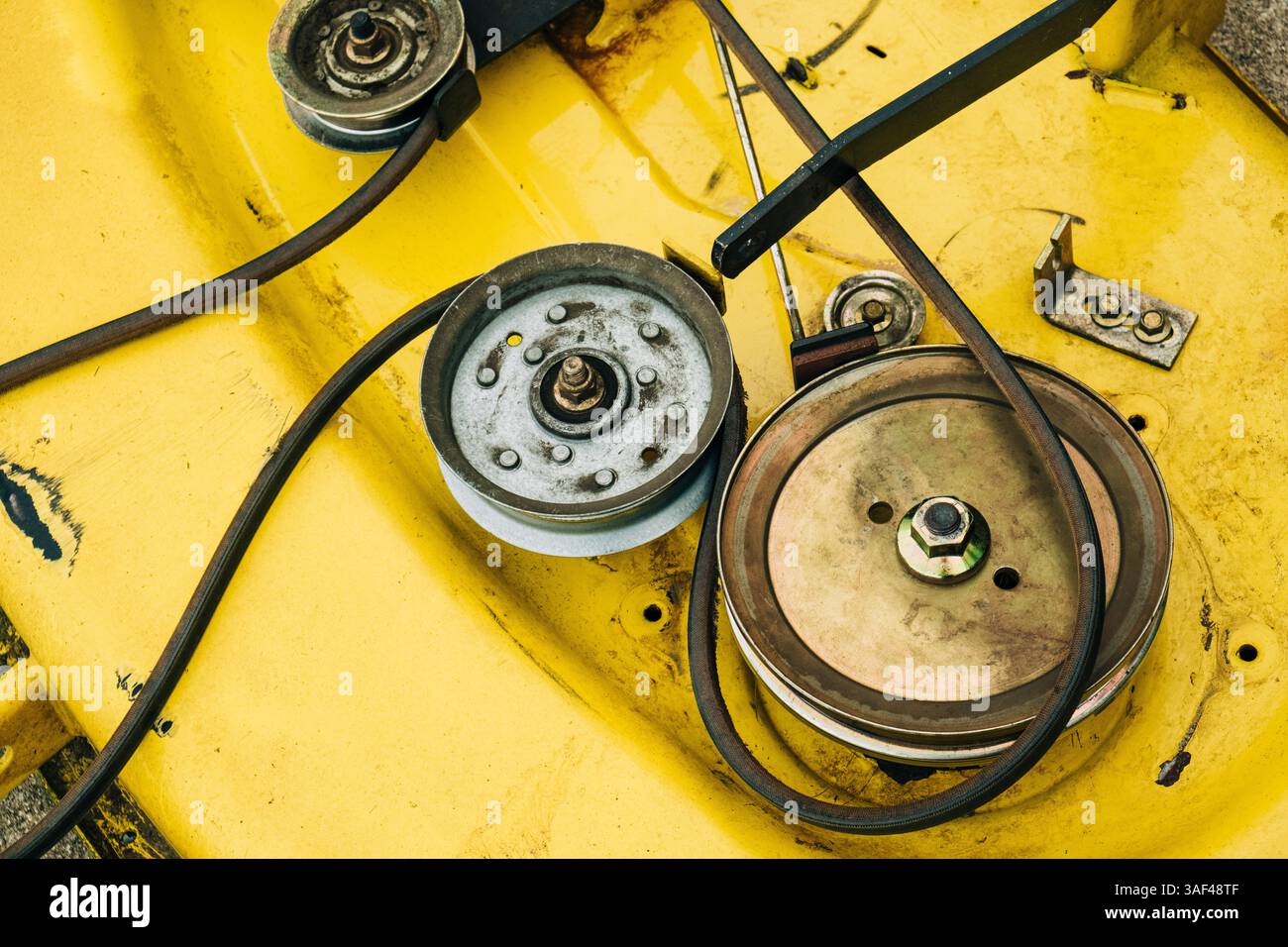Close-up view of mechanical components on a bright yellow mower deck ...