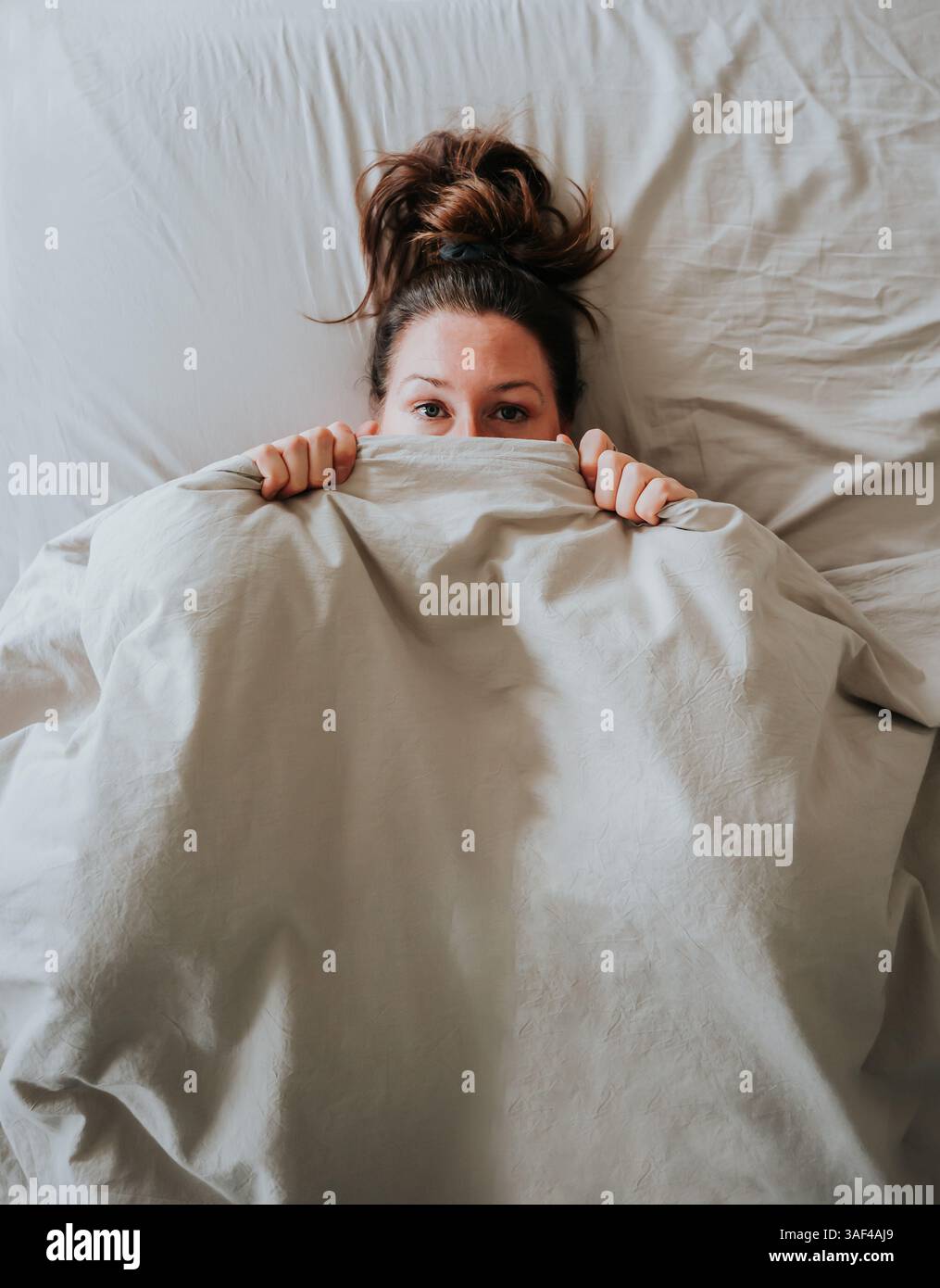Top view of woman in bed hiding under covers with blanket over face ...