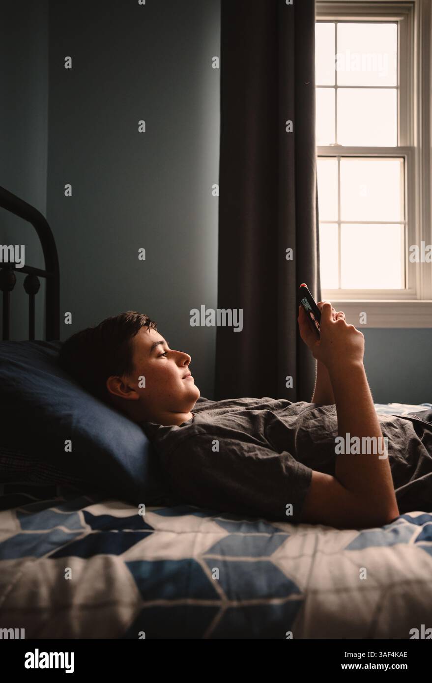 Teen boy in bedroom using smartphone while laying on his bed Stock ...