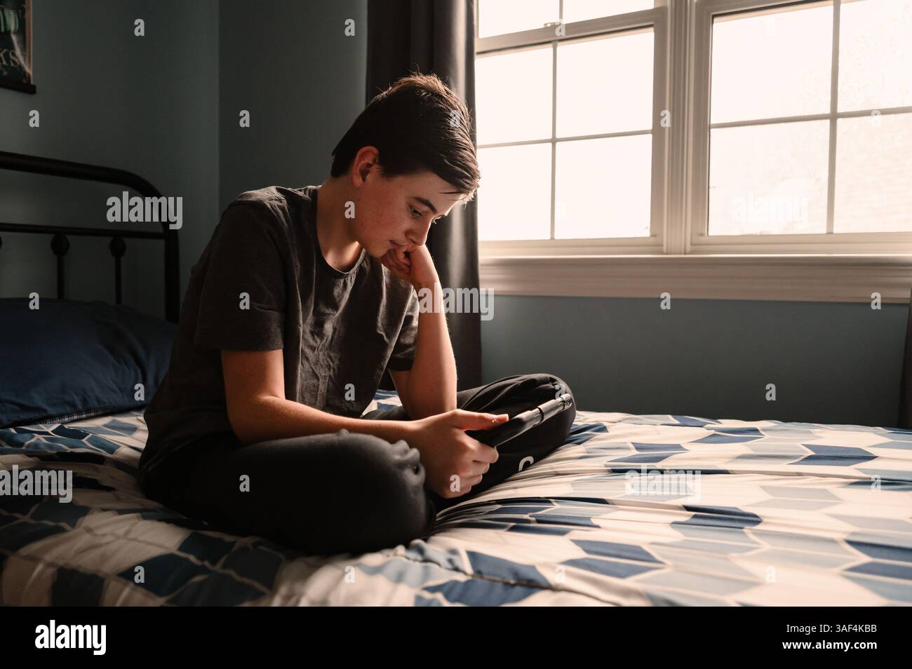 Teen boy in bedroom watching something on ipad tablet on his bed Stock ...