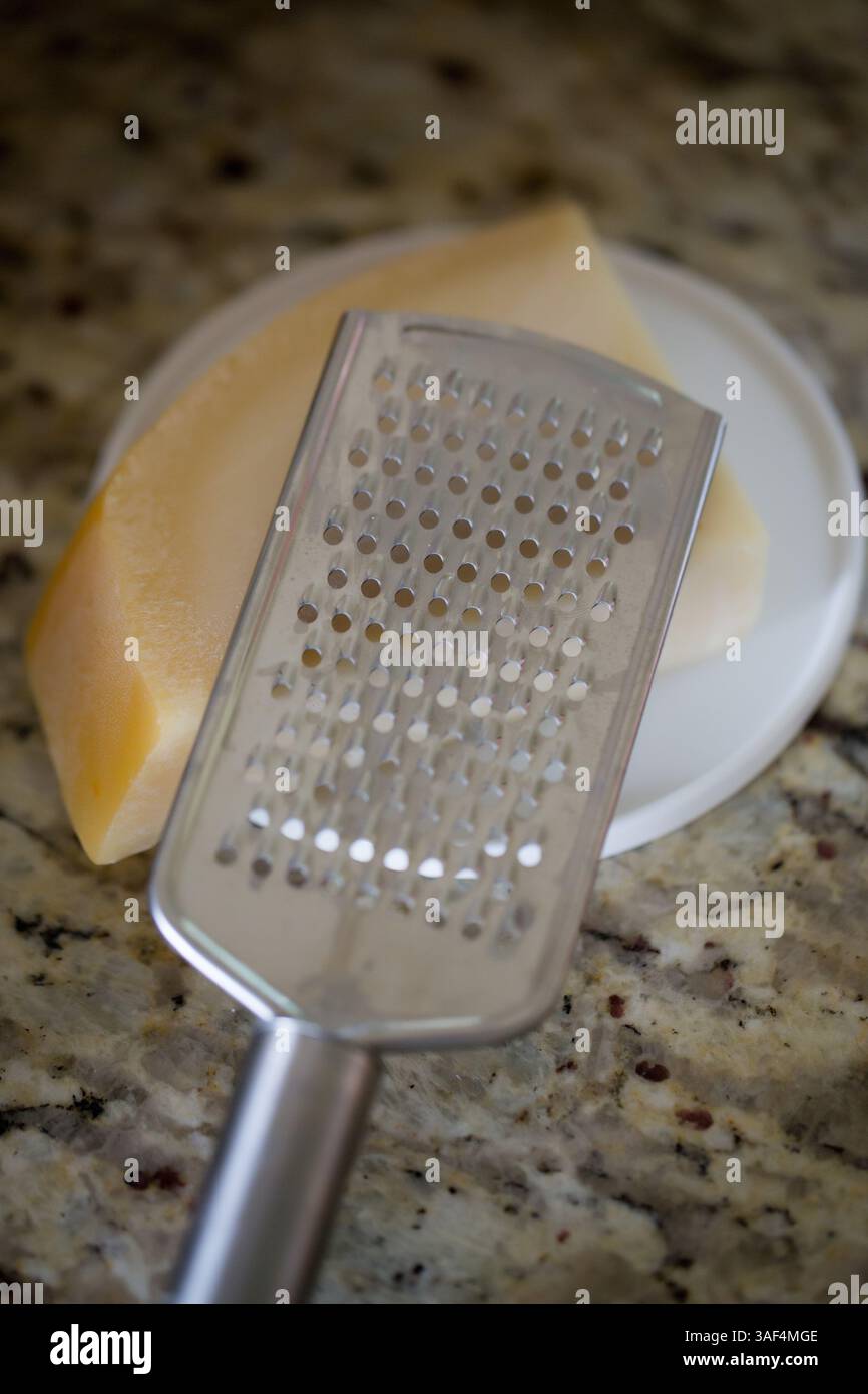 Metal cheese grater resting on a wedge of hard cheese Stock Photo - Alamy