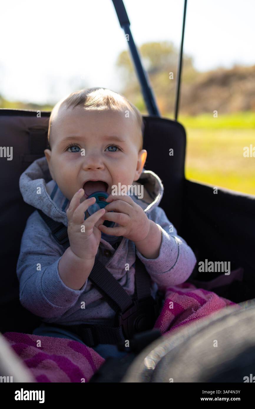 Baby putting a pacifier in their mouth Stock Photo - Alamy