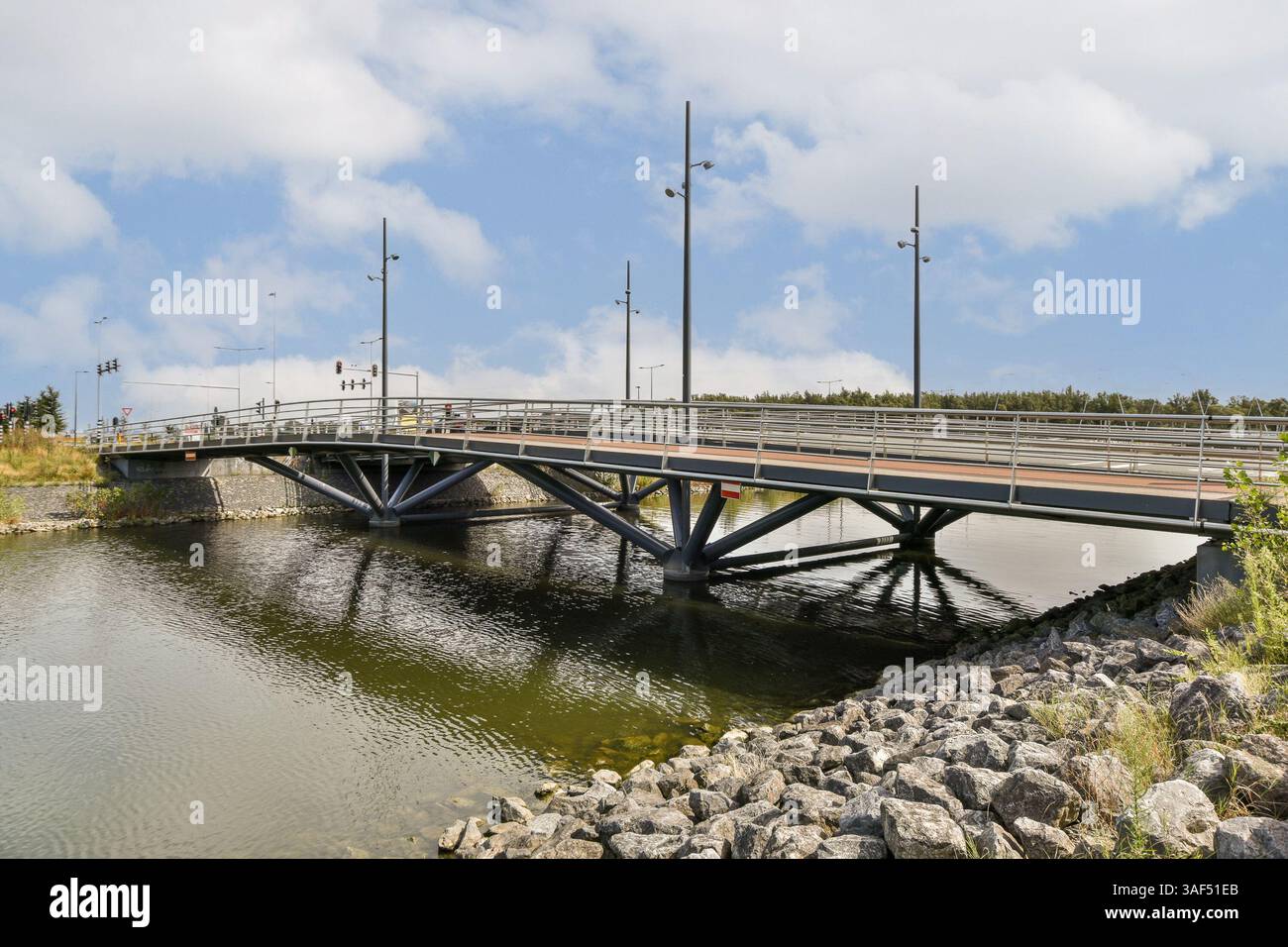 A sleek modern bridge spans over a tranquil body of water, surrounded ...