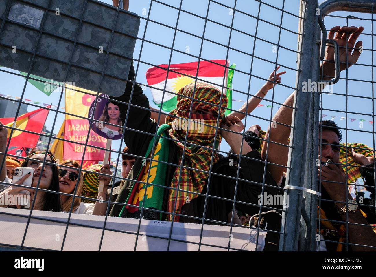 People stand in front of the flag of the Kurdish Regional Government of ...