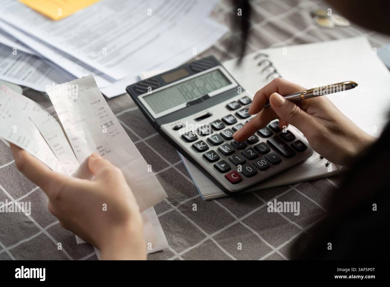 Individual calculating expenses using a calculator and receipts on a ...