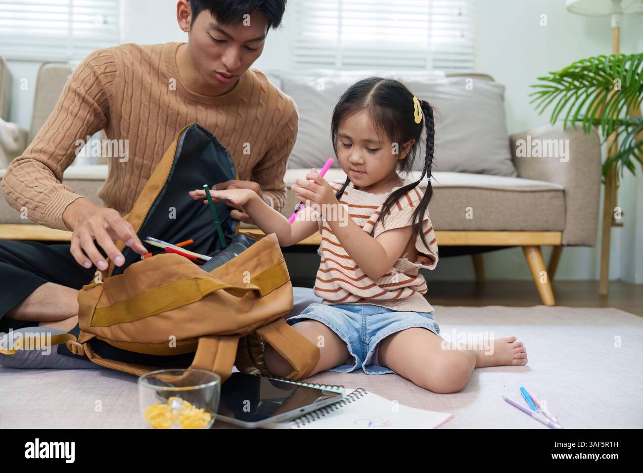 Organization and Creativity. A father helps his daughter organize her school supplies, fostering ...