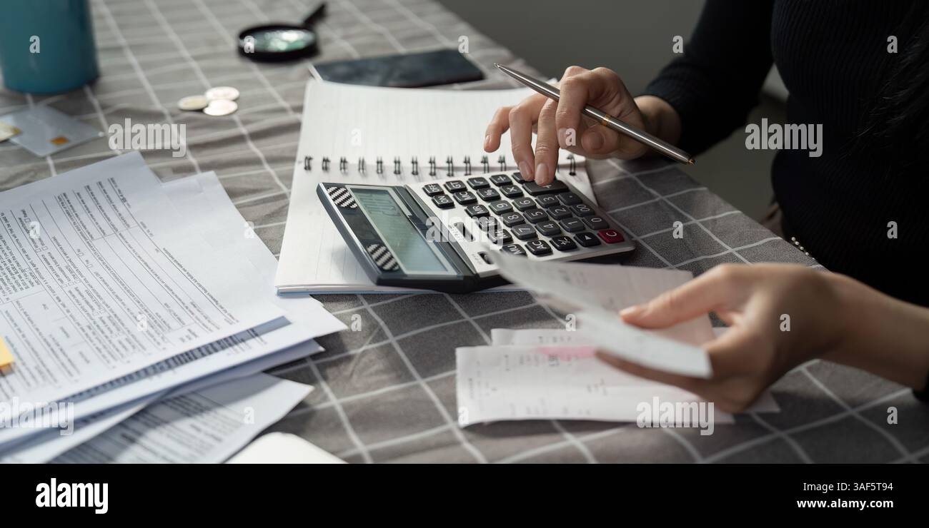 Individual calculating expenses with a calculator and receipts on a ...
