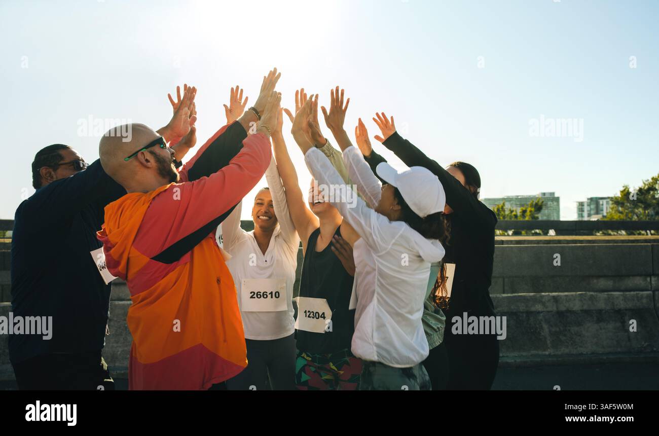 A group of runners proudly celebrate their achievement by sharing a ...