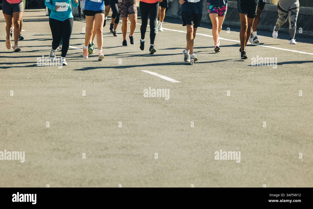 A group of marathon runners are captured mid-stride on a tarmac road ...
