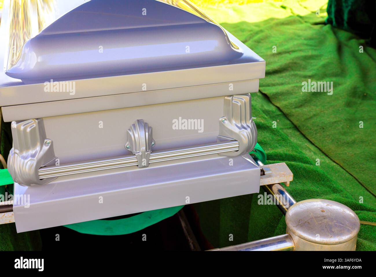 Silver coffin is placed on green cloth, ready for burial service during ...