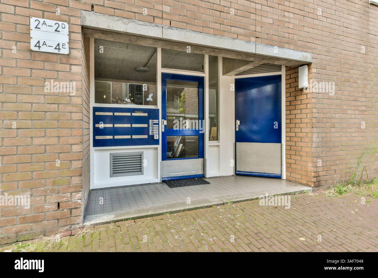 A contemporary entrance featuring blue doors and a brick facade, set in ...