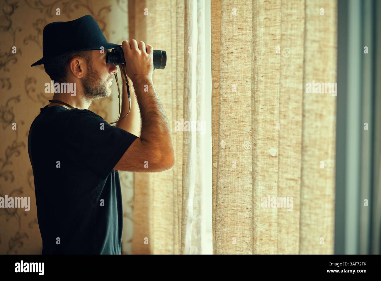 Man in fedora hat looking through binoculars spying from window. Spy ...