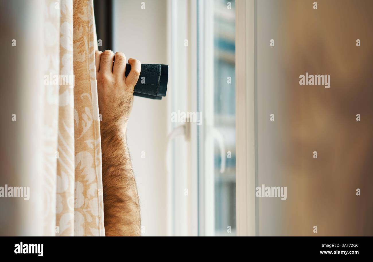 Arm holding binoculars peeking through curtain. Spy at work Stock Photo ...