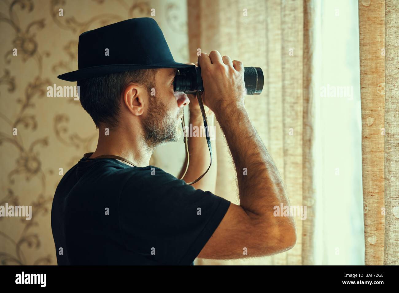 Man in fedora hat looking through binoculars spying from window. Spy ...