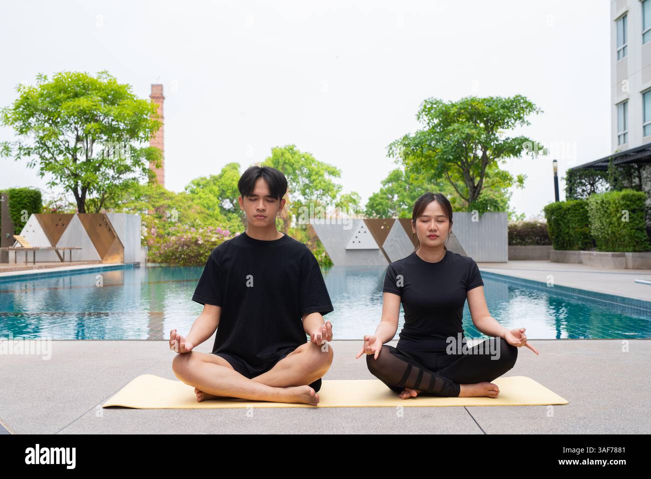 Young Asian couple doing yoga and meditation together next to swimming pool Stock Photo - Alamy