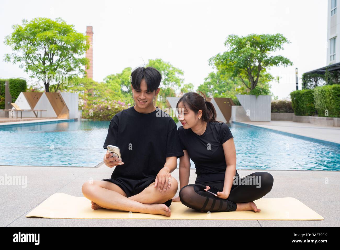 Young sporty couple doing yoga and using phone together next to ...