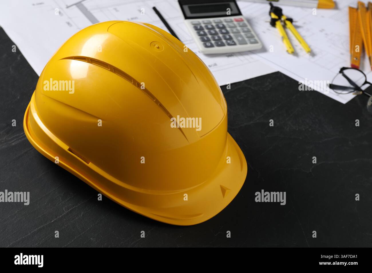 Hard hat, different engineering drawings and tools on black table ...