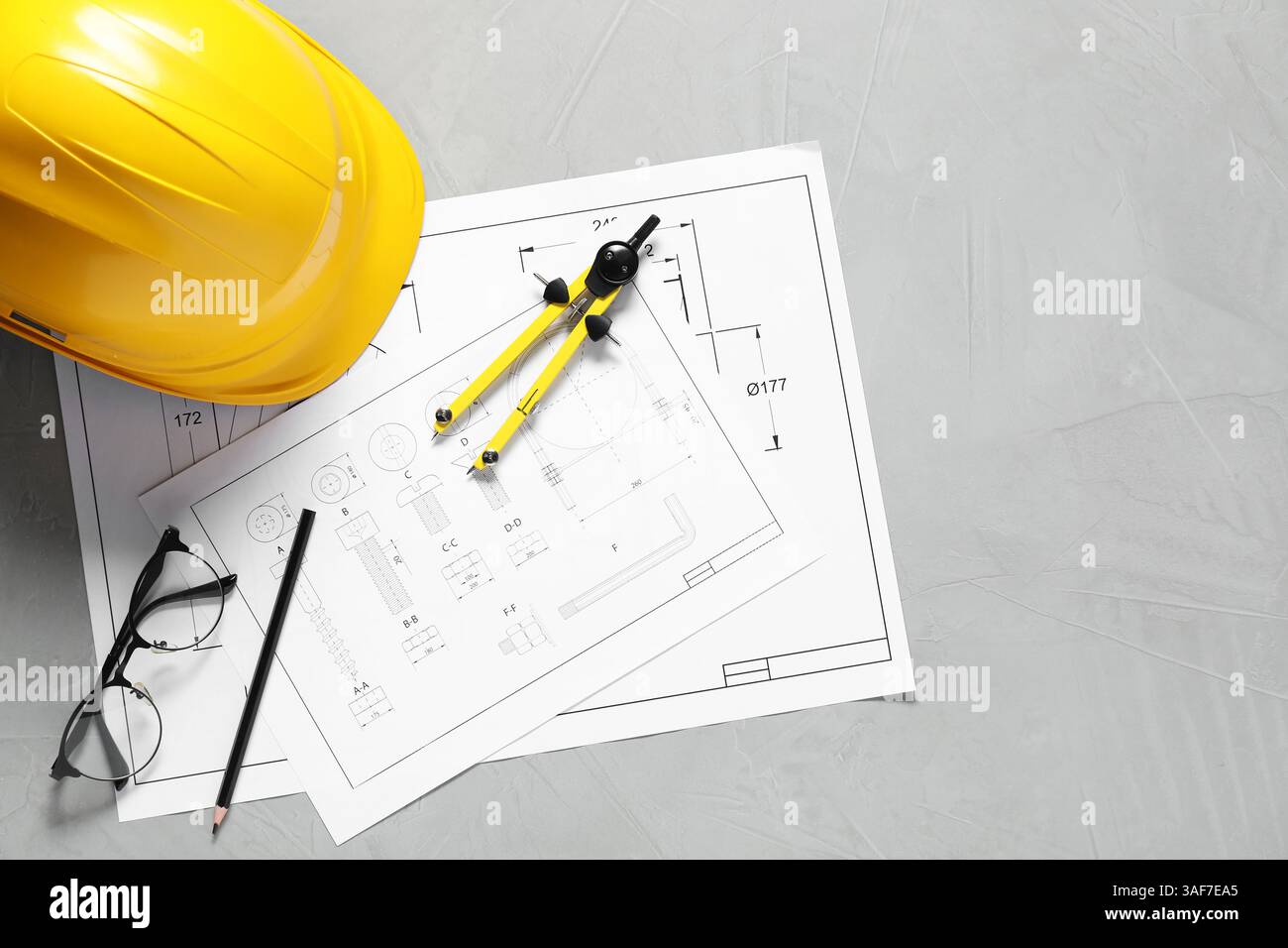 Different engineering drawings, hard hat, pencil, divider and glasses ...