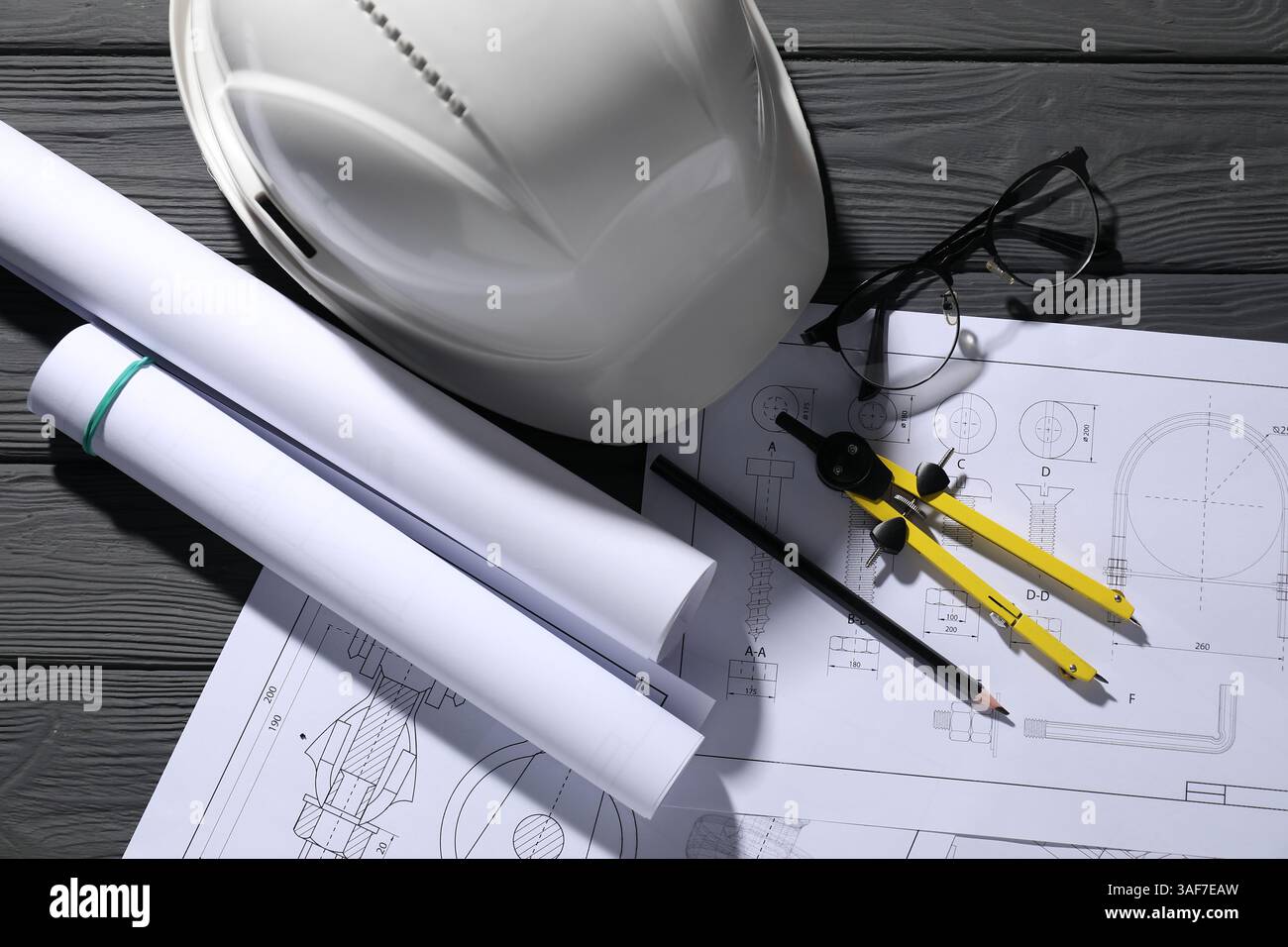 Different engineering drawings, hard hat, glasses, pencil and divider ...