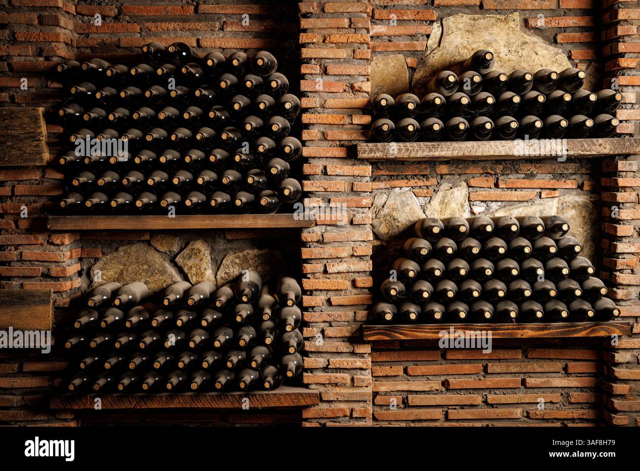A collection of wine bottles arranged on shelves made of wood and ...