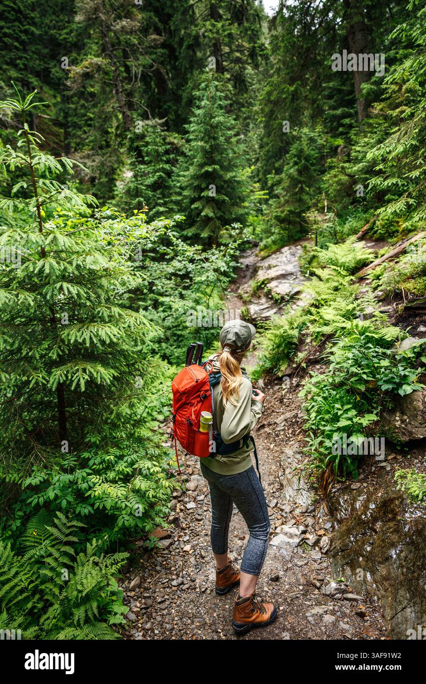 Solo hiking in wilderness. Woman with backpack walks on footpath in ...