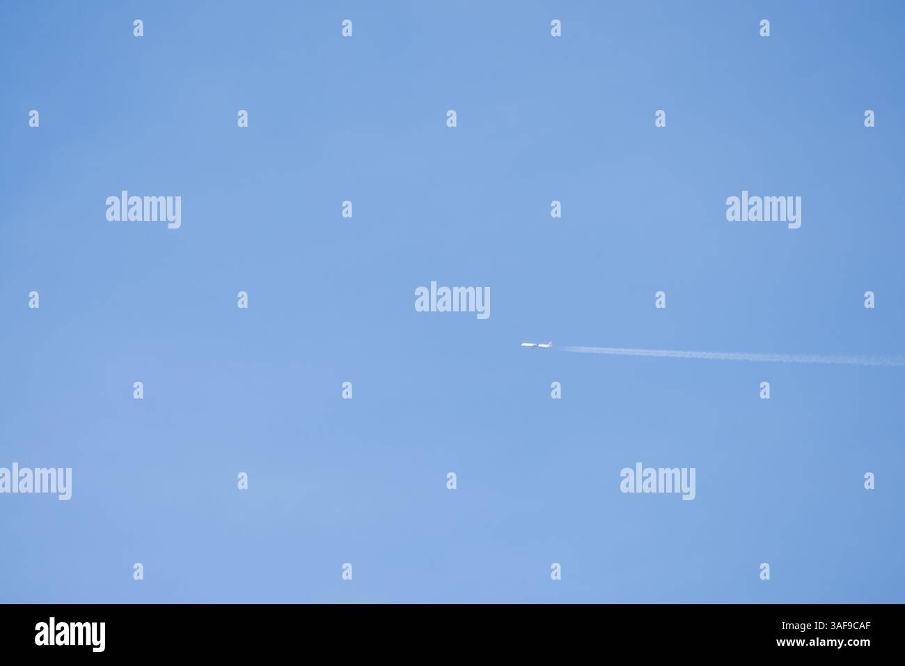 twin engined jet liner aircraft in deep blue sky, contrails vapour ...