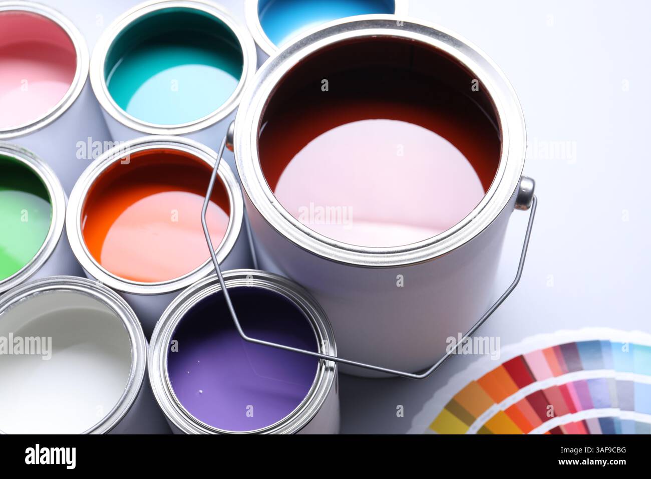 Cans of bright paints and color palettes on light background, closeup ...