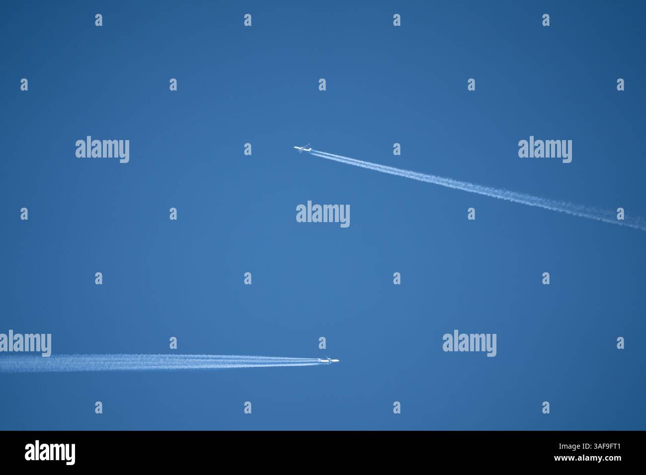 a pair of twin engined jet liner aircraft in deep blue sky, contrails ...